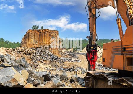Basalt mining. Excavators in a basalt quarry near the forest. Large ...
