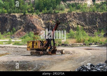 Basalt mining. Excavators in a basalt quarry near the forest. Large ...