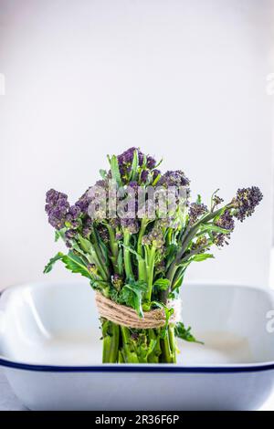 Purple sprouting broccoli in an enamel pot and a vase of spring flowers ...