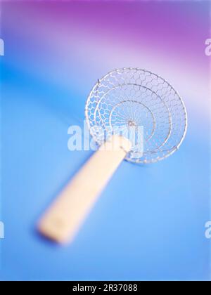 A Chinese fry sieve against a coloured background Stock Photo - Alamy