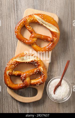 Wooden board with soft pretzels on black background Stock Photo - Alamy