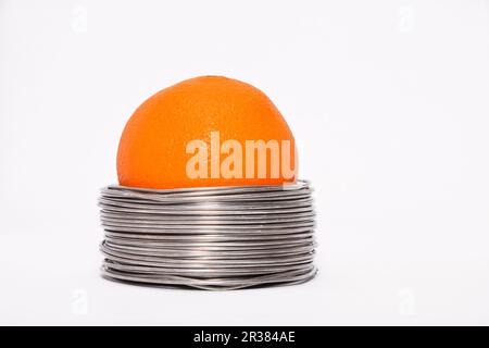Wired orange: whole orange in coils of aluminium wire isolated on white ...