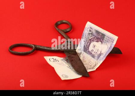 Scissors cut British Pound over red background Stock Photo - Alamy