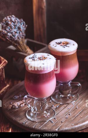 Glass of tasty lavender latte, coffee beans and flowers on color ...