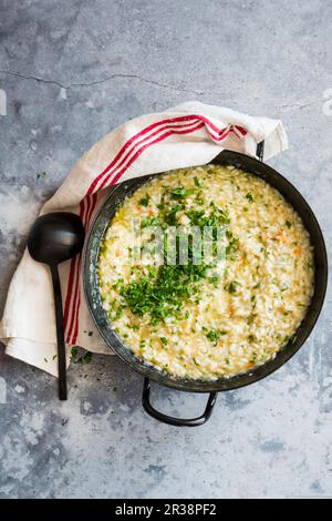 An overhead photo of a seafood risotto on a dark rustic background ...