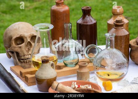 Table of medieval apothecary with bottles jars and skull Stock Photo ...