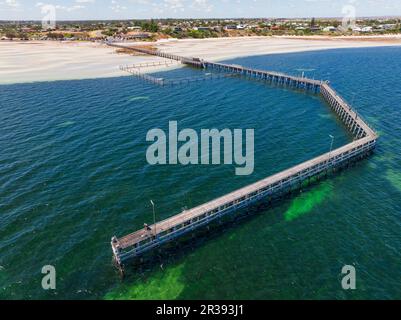 Aerial view of a long narrow jetty stretching out into a calm coastal ...