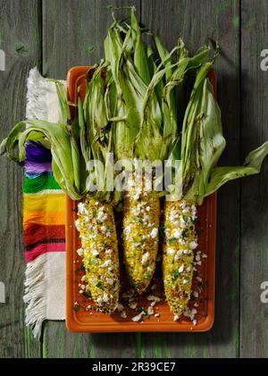 Grilling mexican street corn elote garnished with spices and fresh ...