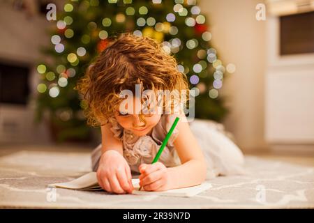 Little curly girl writing letter on the floor Stock Photo - Alamy