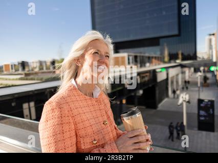 Woman smiling, holding a reusable coffee cup, inside a car Stock Photo ...