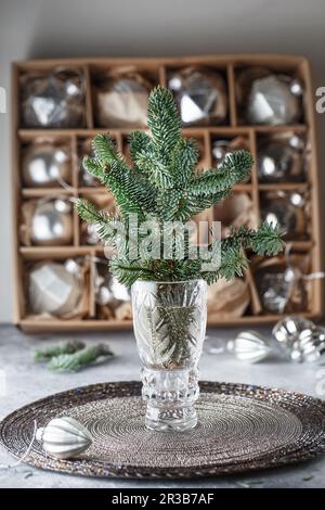 Vase with tree branches, Christmas balls and gift on table in living ...