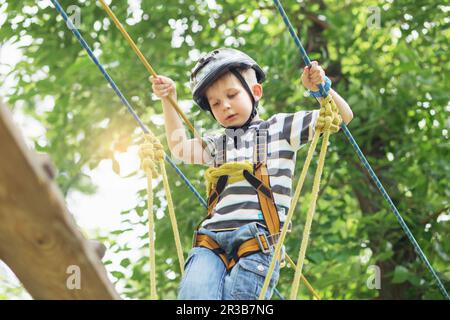 Boy enjoys climbing in the ropes course adventure. Happy boys playing ...