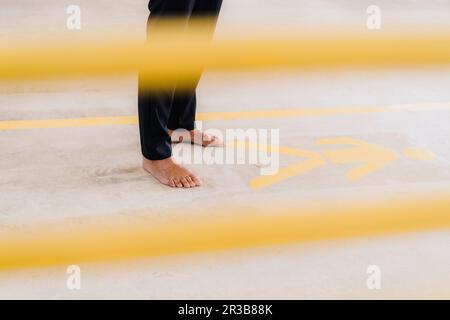 Businessman standing barefoot by sign on floor in factory Stock Photo ...