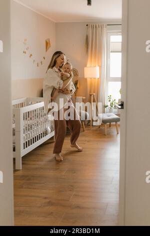 Mother cradling baby in nursery room Stock Photo - Alamy