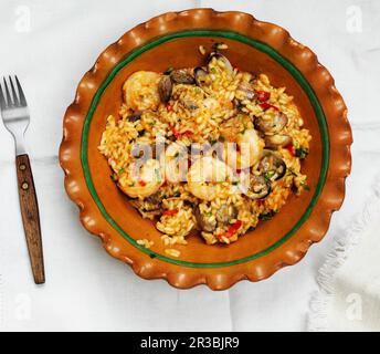 An overhead photo of a seafood risotto on a dark rustic background ...