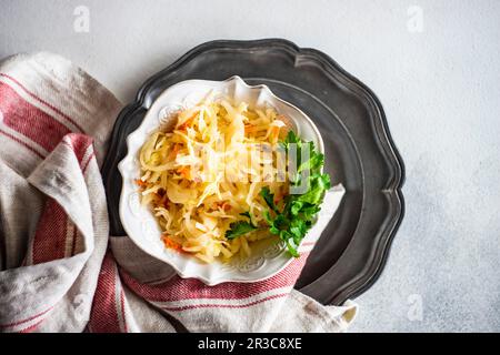 Fermented cabbage in ceramic bowl on table with spices and ingredients ...