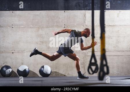 A muscular man captured in air as he jumps in a modern gym, showcasing ...