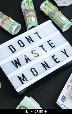Lightbox board with word DONT WASTE MONEY in black letters around euro ...