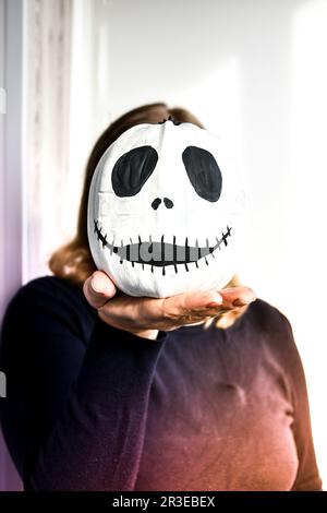 Woman holding Funny pumpkin face in front of her face. Halloween ...