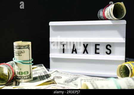 Lightbox board with word TAXES in black letters around Euro banknotes ...