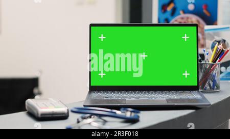Empty reception desk with greenscreen on laptop display, hospital lobby ...