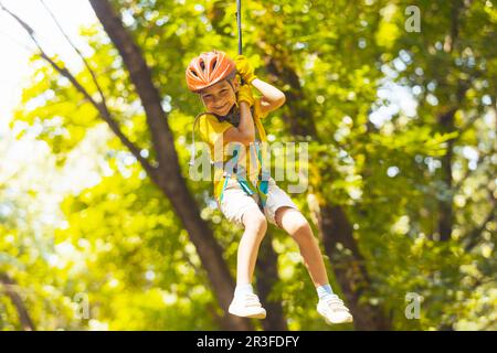 The little boy goes down the zipline in the park Stock Photo - Alamy