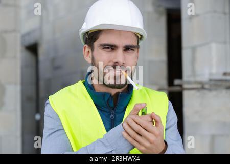 happy builder smoking cigarette on construction site Stock Photo - Alamy