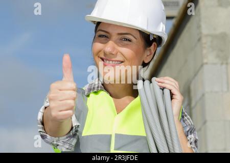 Portrait of female worker carrying reel of cable Stock Photo - Alamy