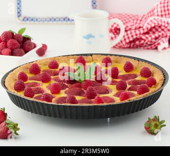 Round quiche with red strawberries and raspberries on a white table ...