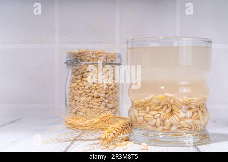 Simple barley orzo infused water drink in glass, with raw and cooked ...