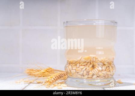 Simple barley orzo infused water drink in glass, with raw and cooked ...