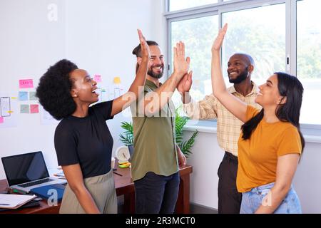 Four diverse team members give high five, celebrate success in creative ...
