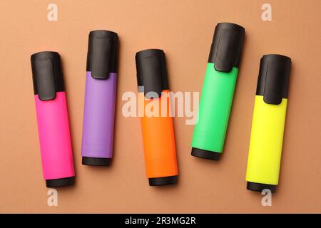 Bright color markers on pale orange background, flat lay. Space for ...
