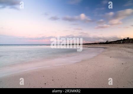 sunset over the picturesque white sand beach and turquoise waters at La ...