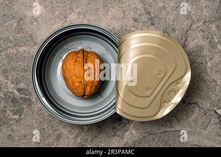 Opened tin can with a single walnut inside. Conceptual image Stock ...