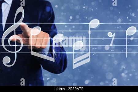 Musician pointing at staff with music notes and symbols on color ...
