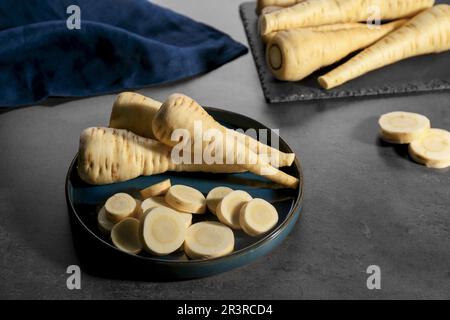 Whole and cut parsnips on black table Stock Photo - Alamy