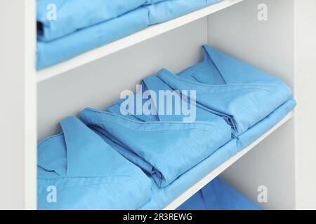 Light blue medical uniforms on rack against white background Stock ...