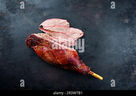 Traditional barbecue leg of venison sliced and served as top view on ...