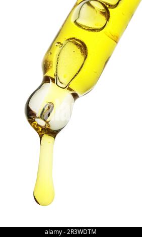 Dripping yellow facial serum from pipette on white background, closeup ...