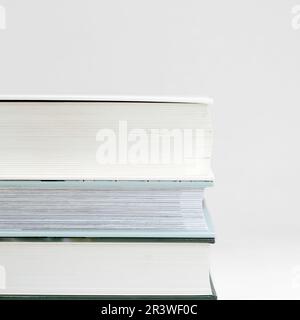 three thick books on a table with a white background Stock Photo - Alamy
