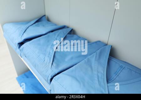 Light blue medical uniforms on rack against white background Stock ...