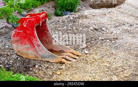 red excavator shovel lying on muddy soil Stock Photo - Alamy
