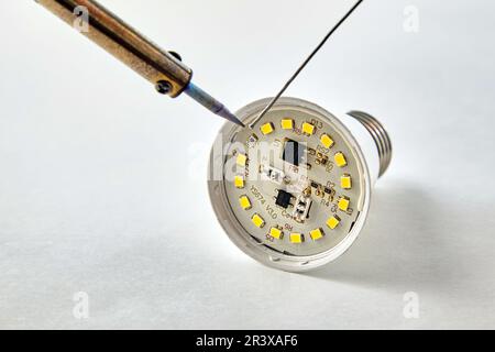 Soldering a burned-out LED into an LED light bulb. Hand with a ...