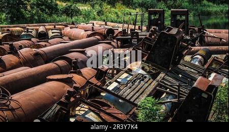 Rusty metal scrapyard on the bank of water reservoir. Remains of metal ...