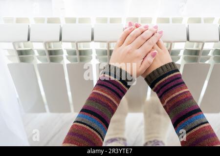 Girl warms up the frozen hands above hot radiator, close up view Stock ...