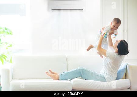 Asian mother and child with air conditioner remote control. Comfortable ...