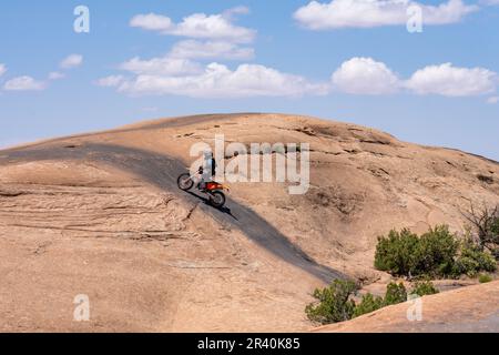 Off road motorcycle climbing a steep sandstone dome of the Fins ...