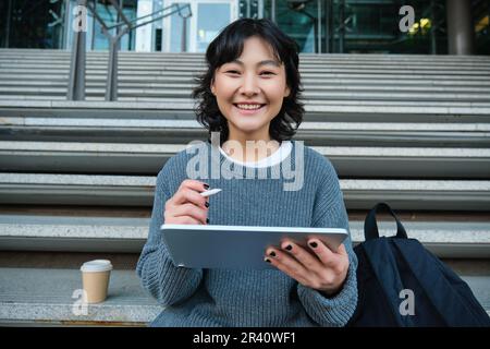 girl artist draws a digital pen on a professional tablet in her studio ...