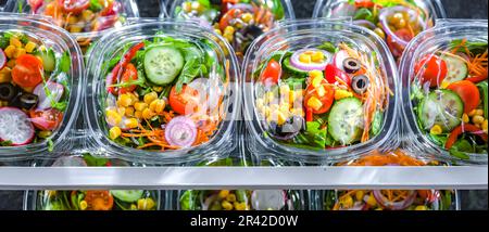 Plastic boxes with pre-packaged vegetable salads, put up for sale in a ...